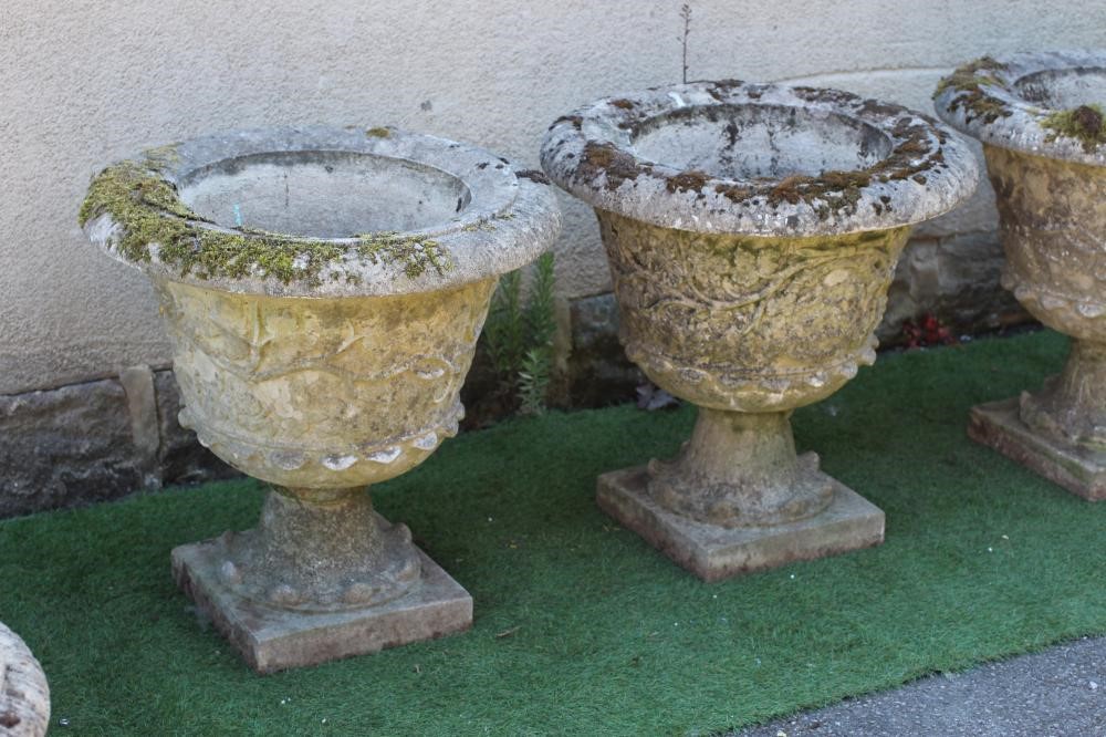 A set of four cast stone urns with everted rim over a body with ...