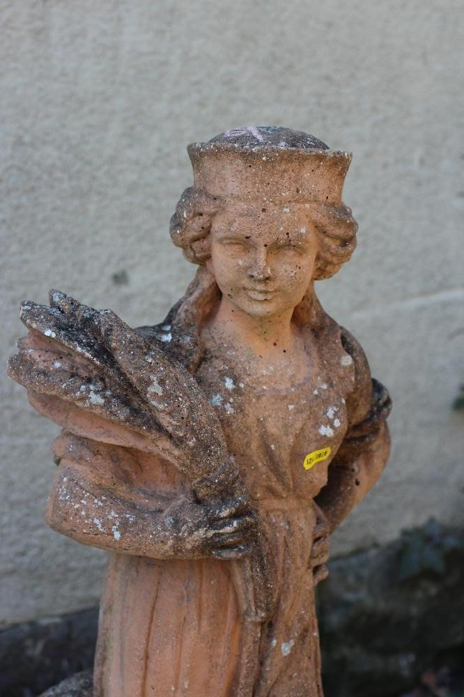 A cast red stone female figure allegorical of autumn, modelled standing ...