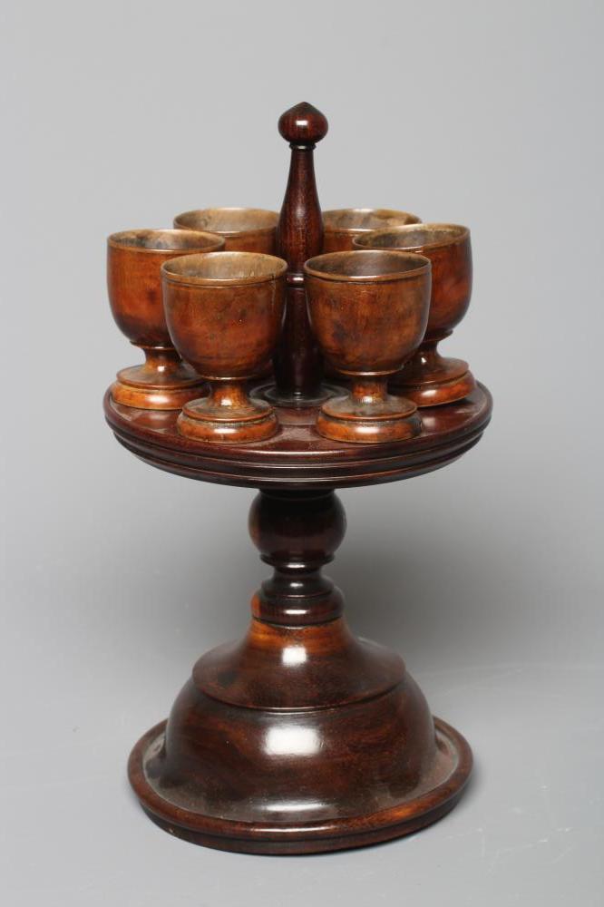 A 19th century turned mahogany egg cruet, with six cups on an upper ...