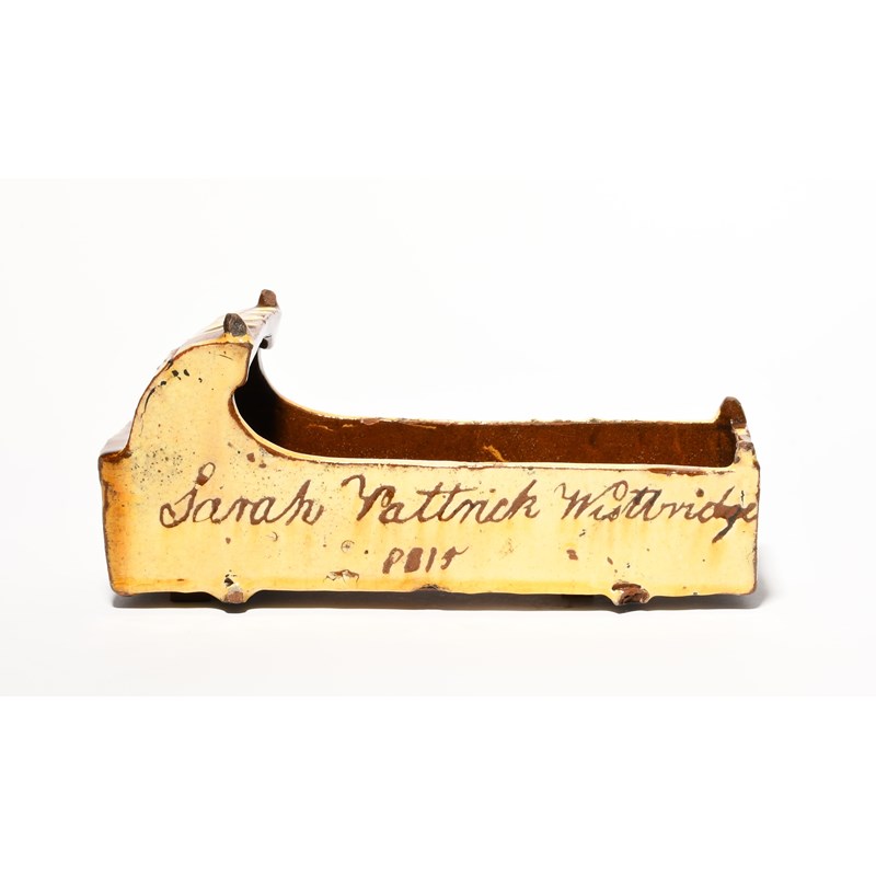A slipware model of a cradle, dated 1815, one side incised 'sarah ...
