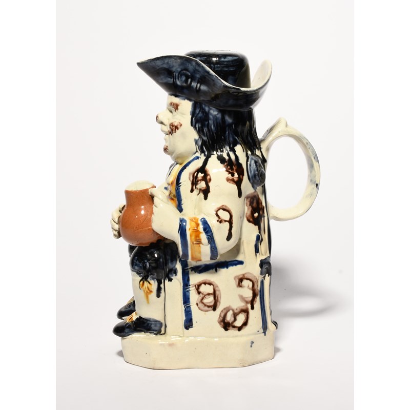 An ordinary toby jug and stopper, c.1800, seated with a foaming jug of ...