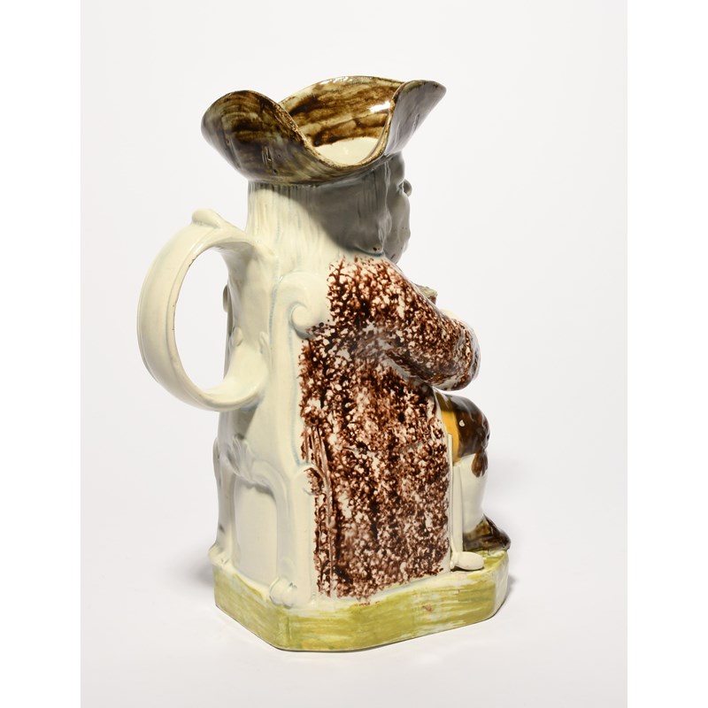 A wood type toby jug, c.1790-1800, seated with a jug of ale and a long ...